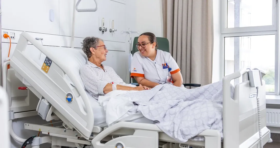 Patiënte oncologie met verpleegkundige aan bed